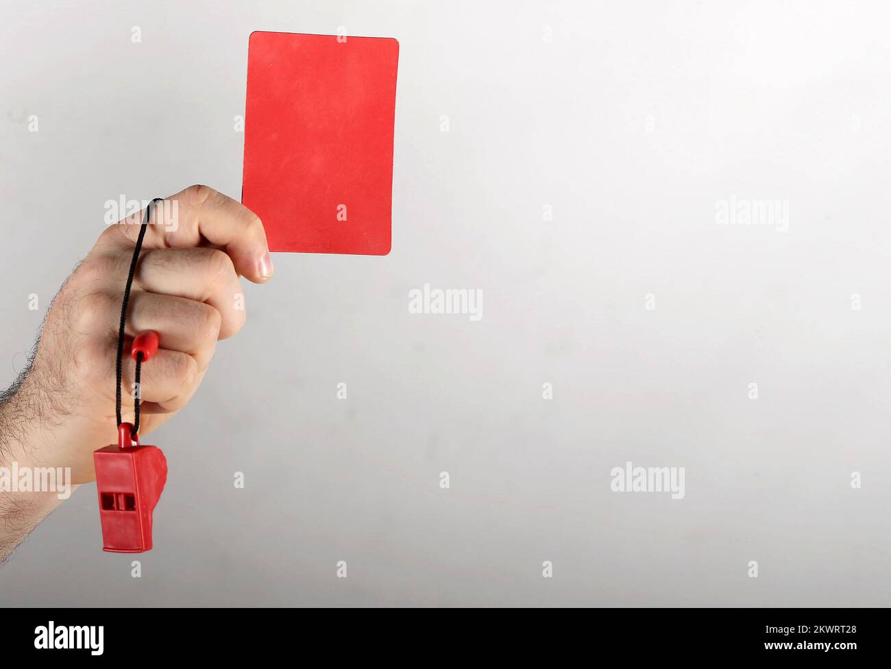 A general view of a man holding up a red card with a referee's whistle ...
