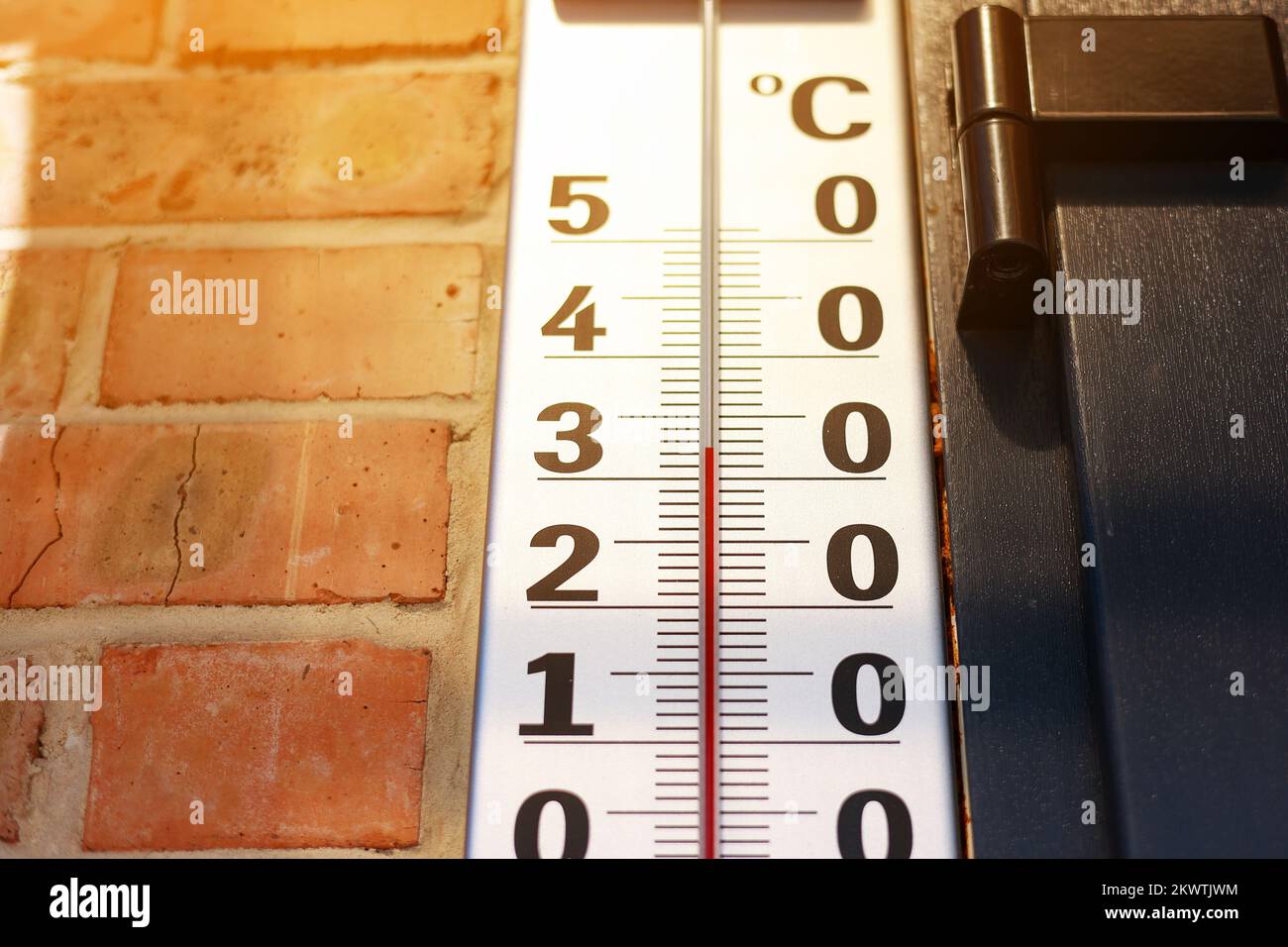 Thermometer showing high hot temperature on brick wall background ...
