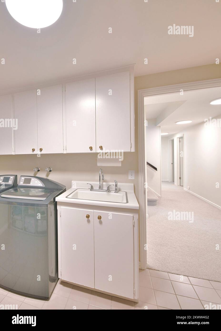 Vertical Interior of a laundry room with an open white door and a view ...
