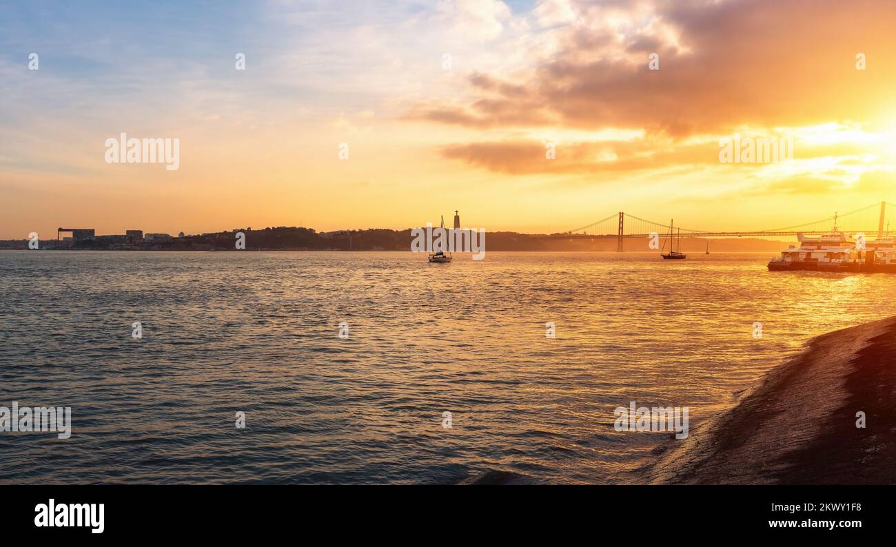 Tagus River (Rio Tejo) at sunset with 25 de Abril Bridge and Sanctuary ...