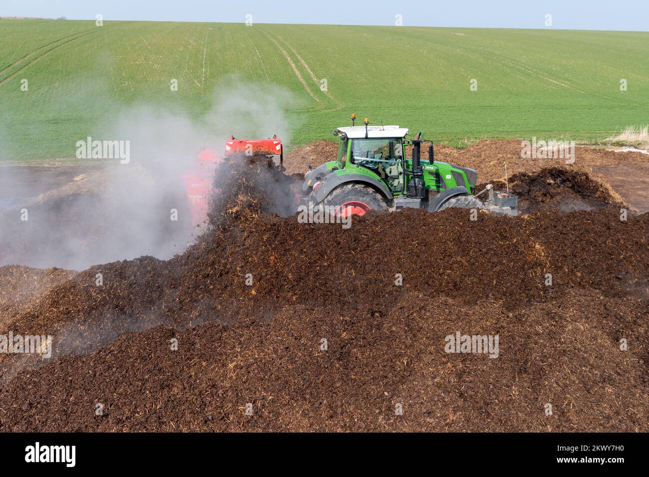 Turning a manure heap over to make compost to spread on farmland, which ...