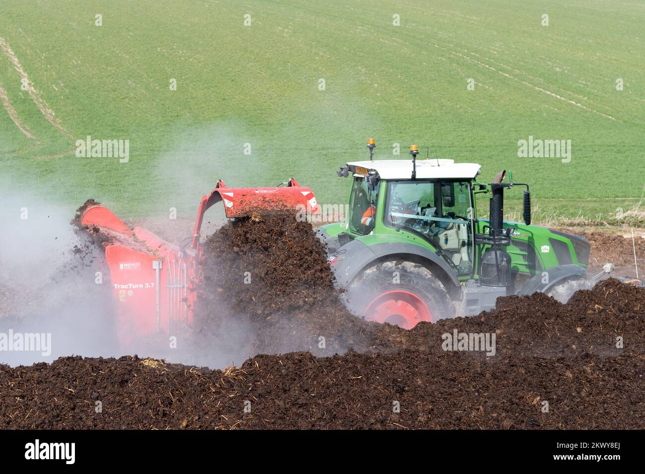 Turning a manure heap over to make compost to spread on farmland, which ...