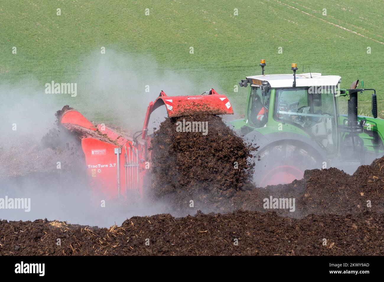 Turning a manure heap over to make compost to spread on farmland, which ...