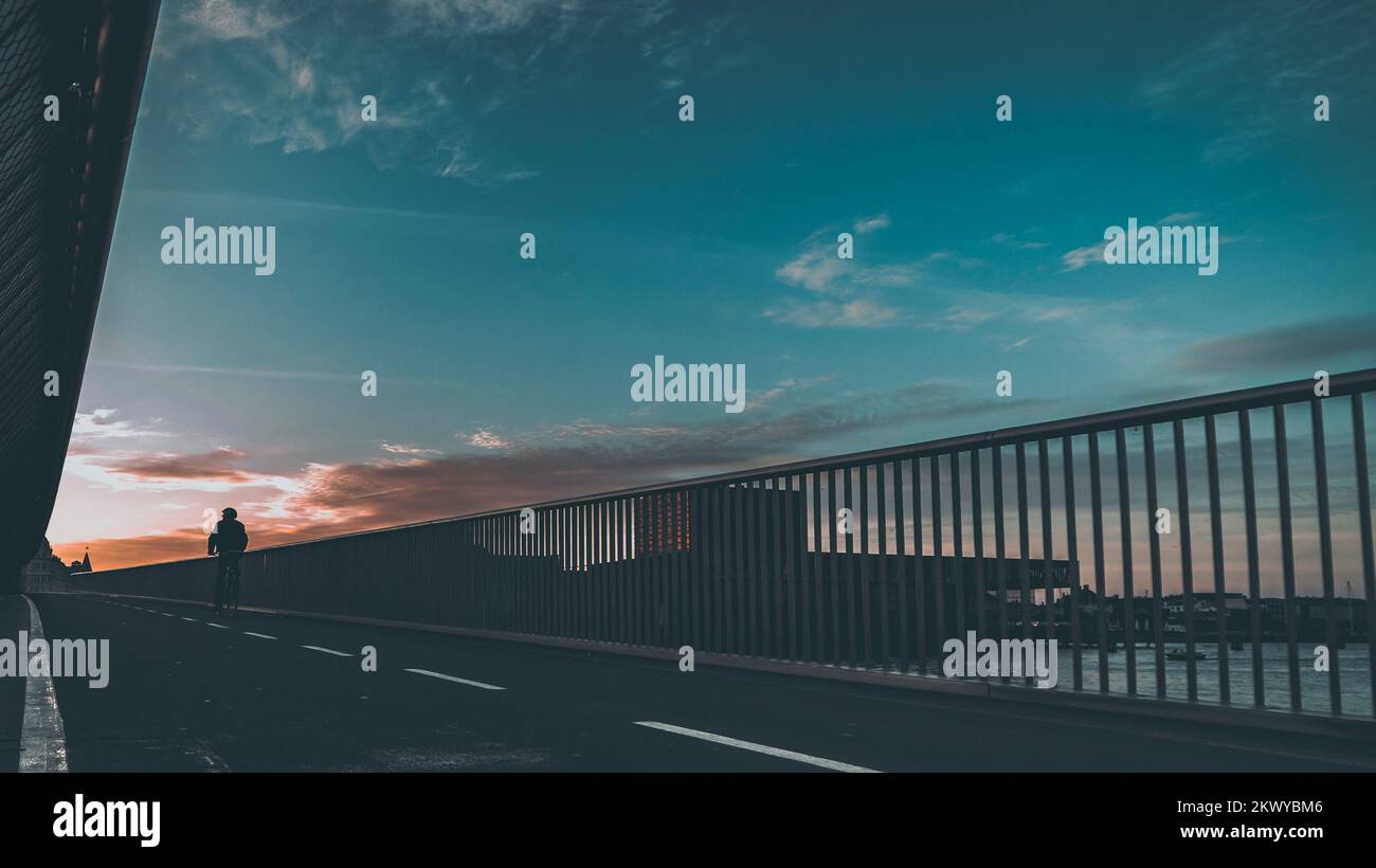 silhouette of the cyclist on the bridge, person riding trough the ...