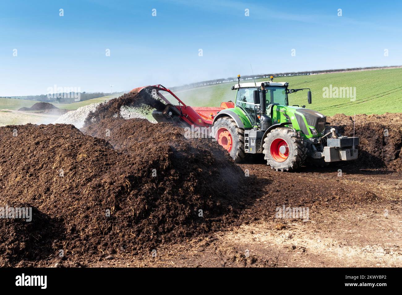 Turning a manure heap over to make compost to spread on farmland, which ...