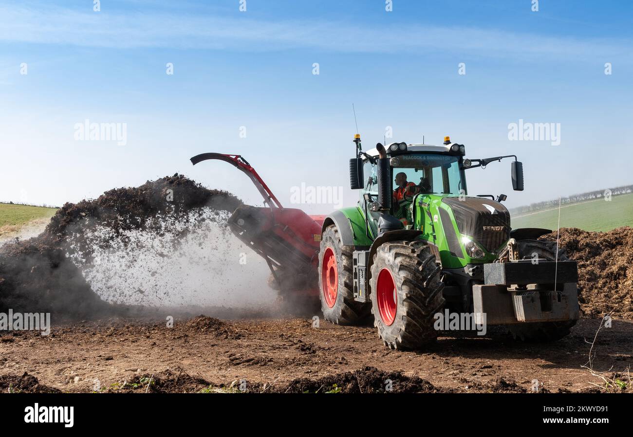 Turning a manure heap over to make compost to spread on farmland, which ...