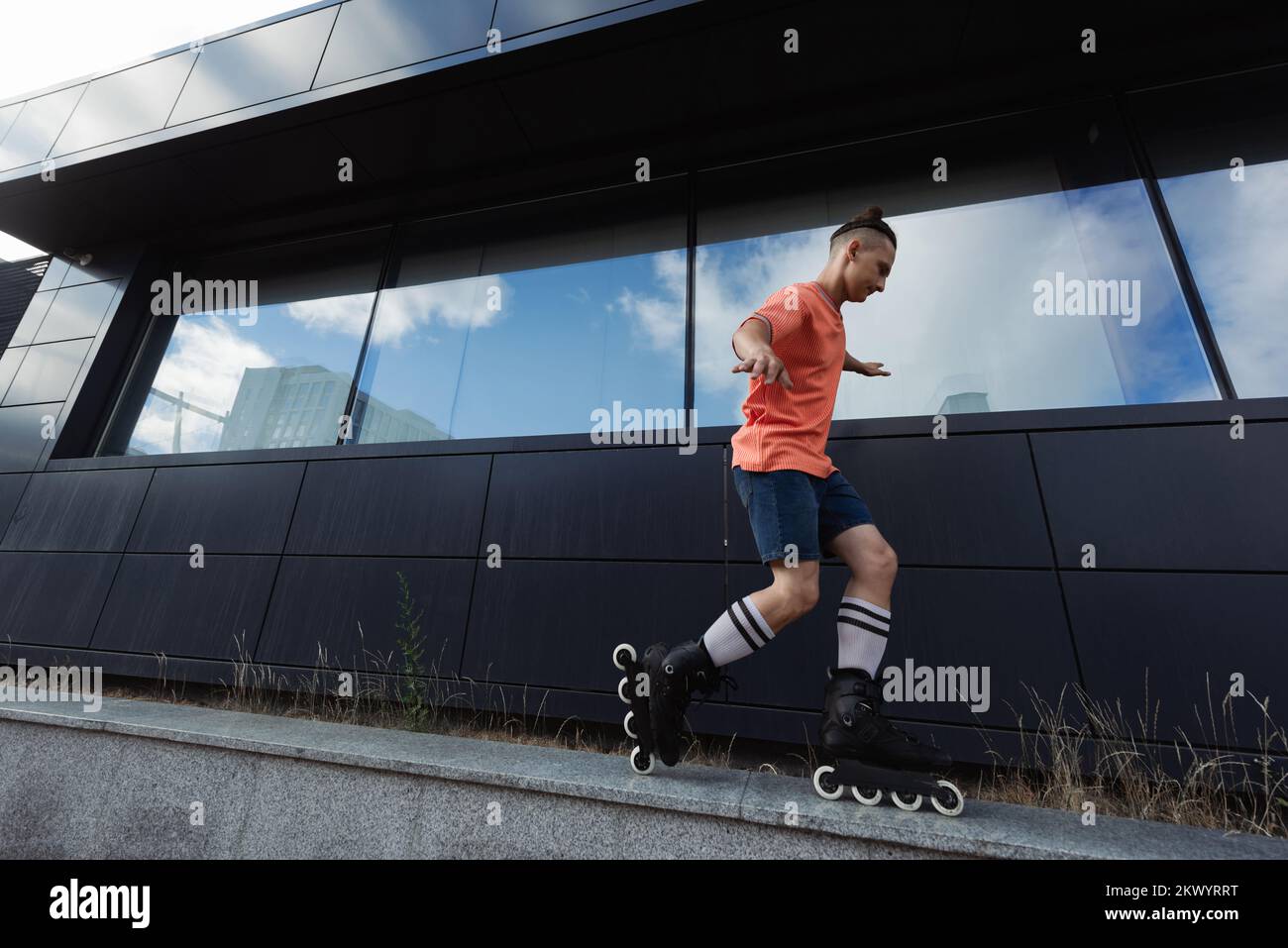 Side view of man in roller blades doing trick on parapet on urban ...