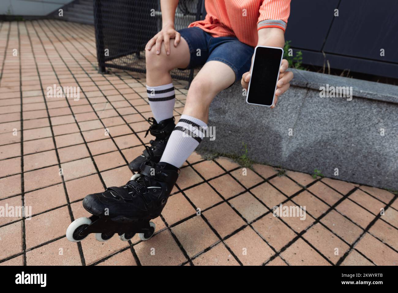 Cropped view of man in rollers and casual clothes showing cellphone ...
