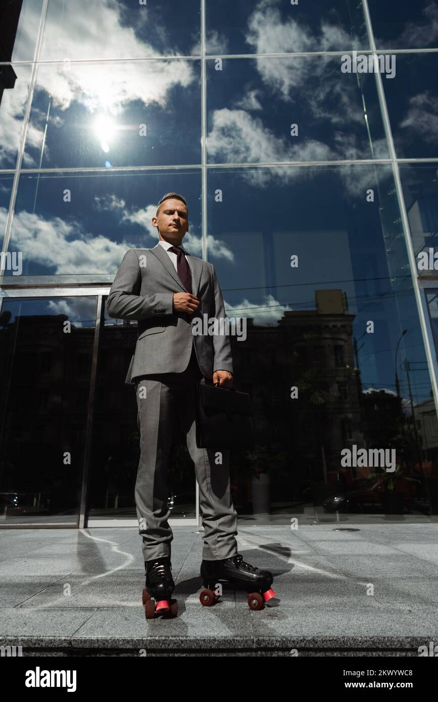 low angle view of confident businessman in grey suit and roller skates ...