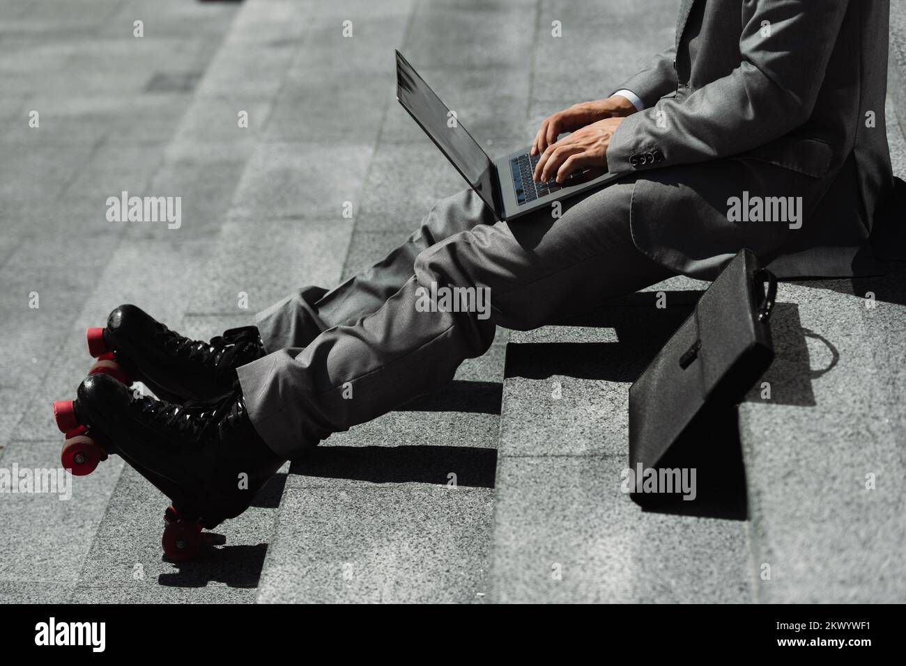 partial view of roller skater in formal wear typing on laptop while ...