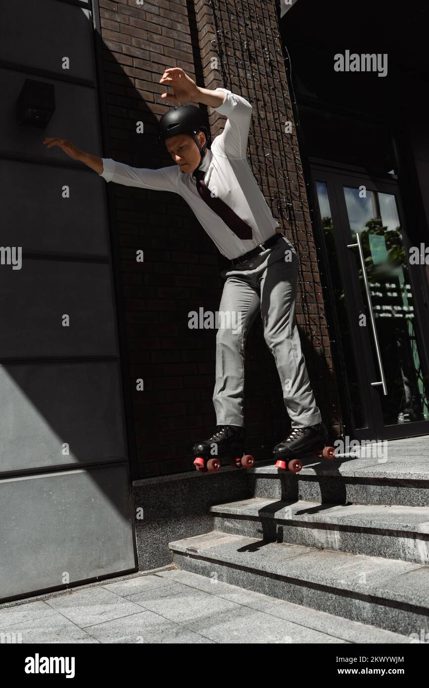 full length of roller skater in formal wear and helmet jumping from ...