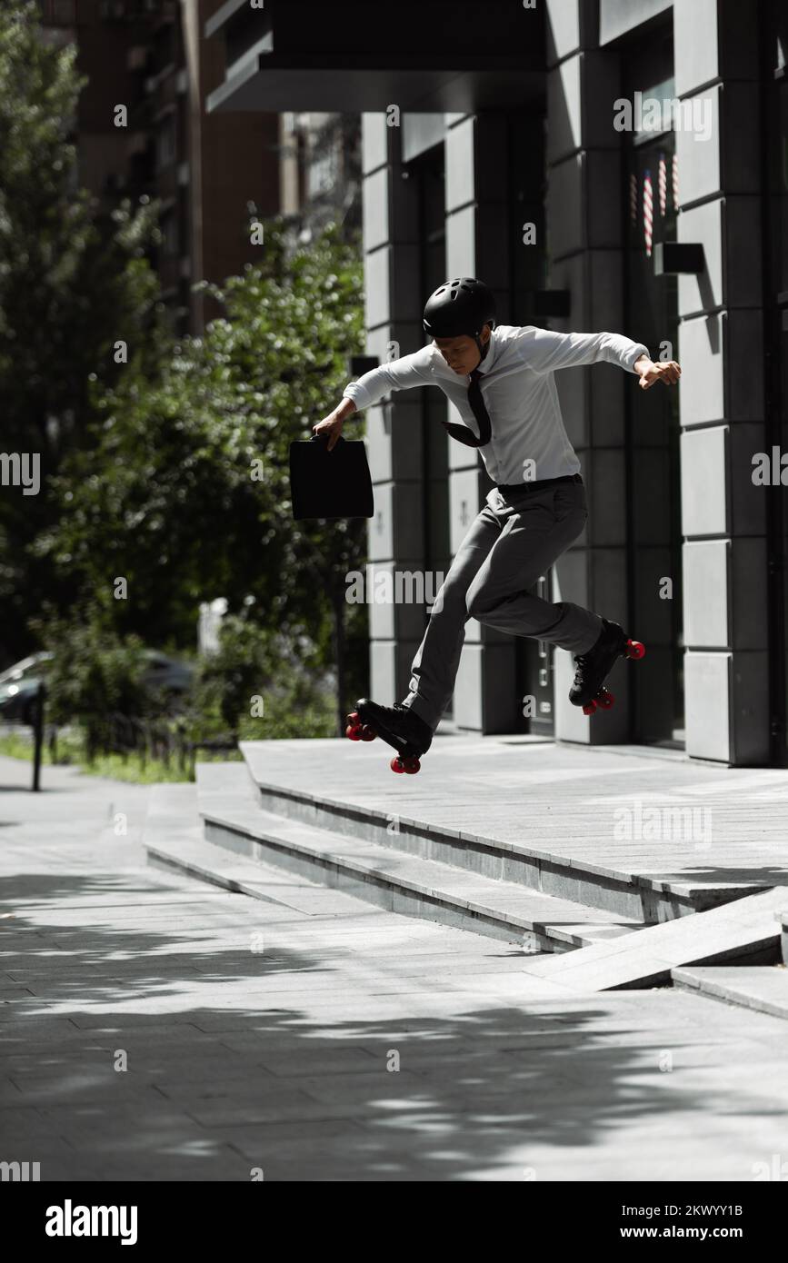 full length of young roller skater in formal wear doing trick and ...