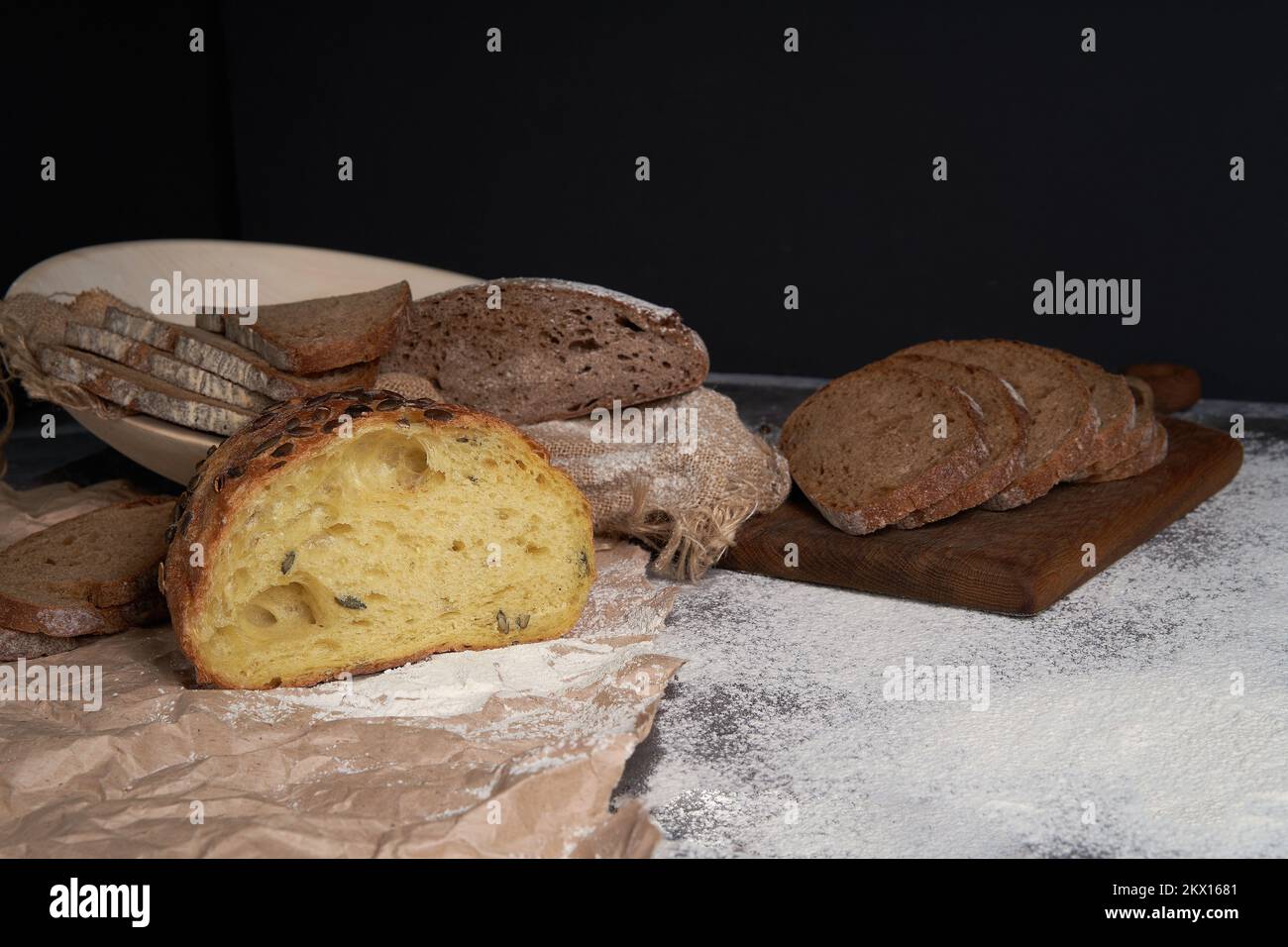 Different types of sliced bread and a loaf on a wooden background ...