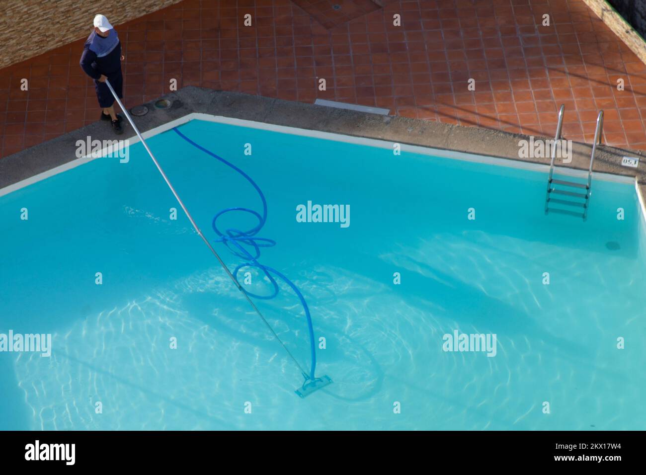 Man cleaning the swimming pool with vacuum equipment. swimming pool ...
