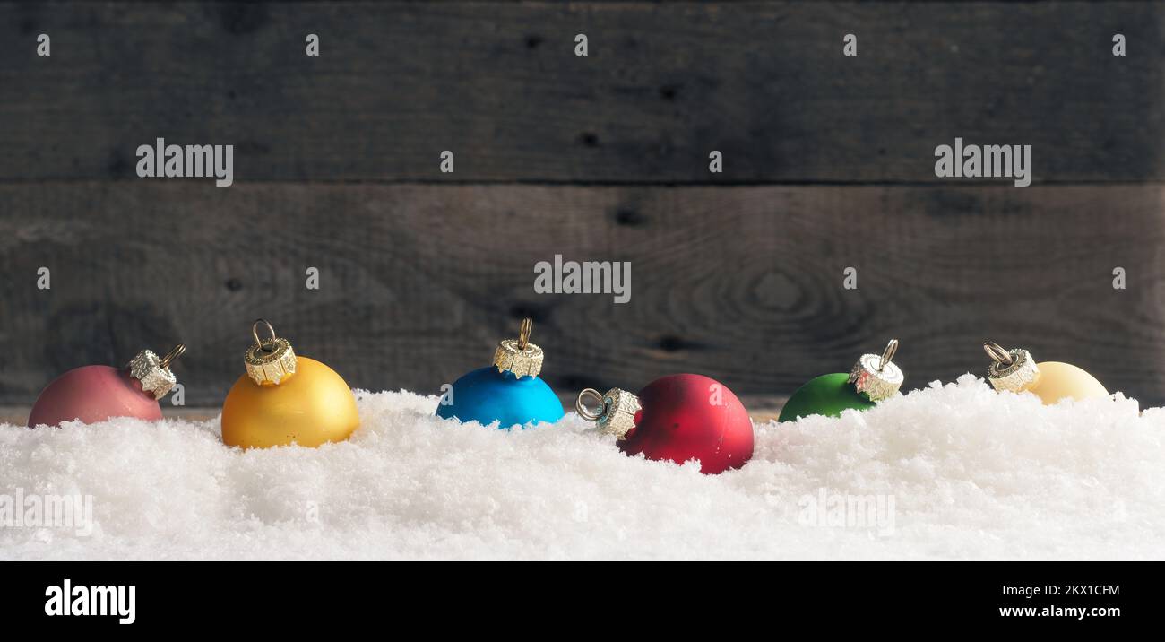 Colorful Christmas baubles in the snow, wooden background with space ...