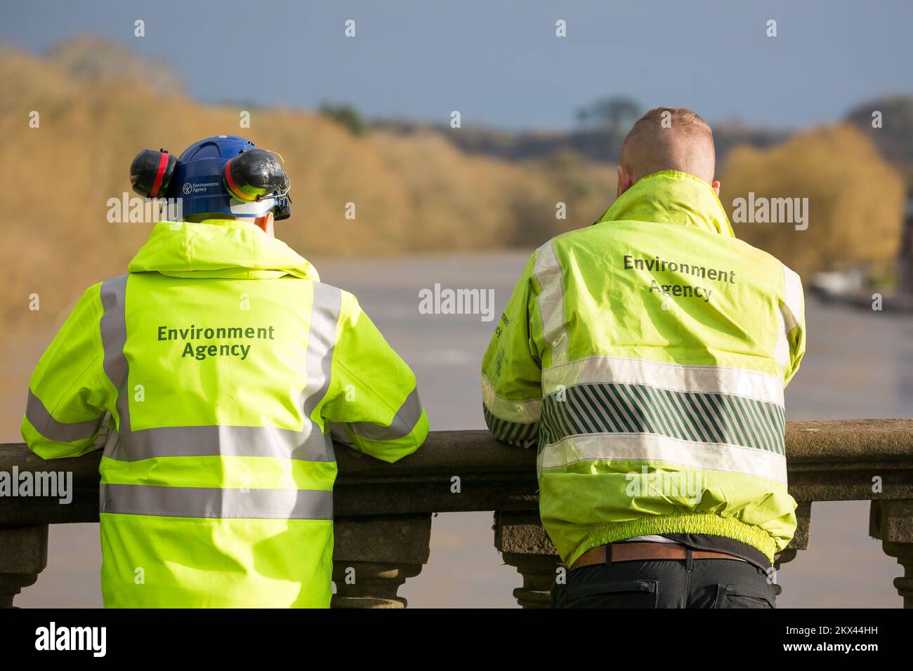 Rear view of two Environment Agency workers looking out over the River ...