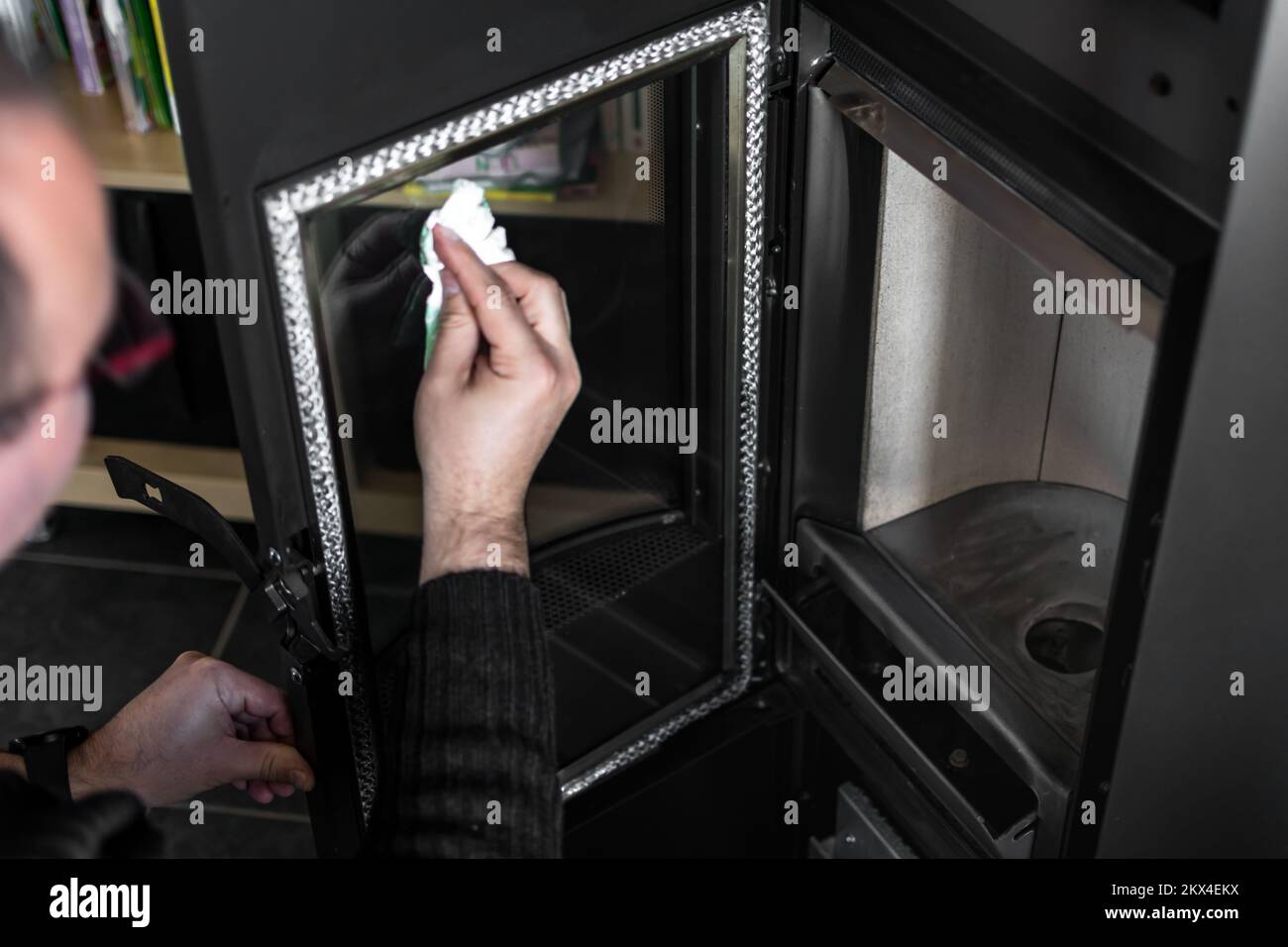 Man cleaning the ash on the glass of a pellet or wood stove with a ...