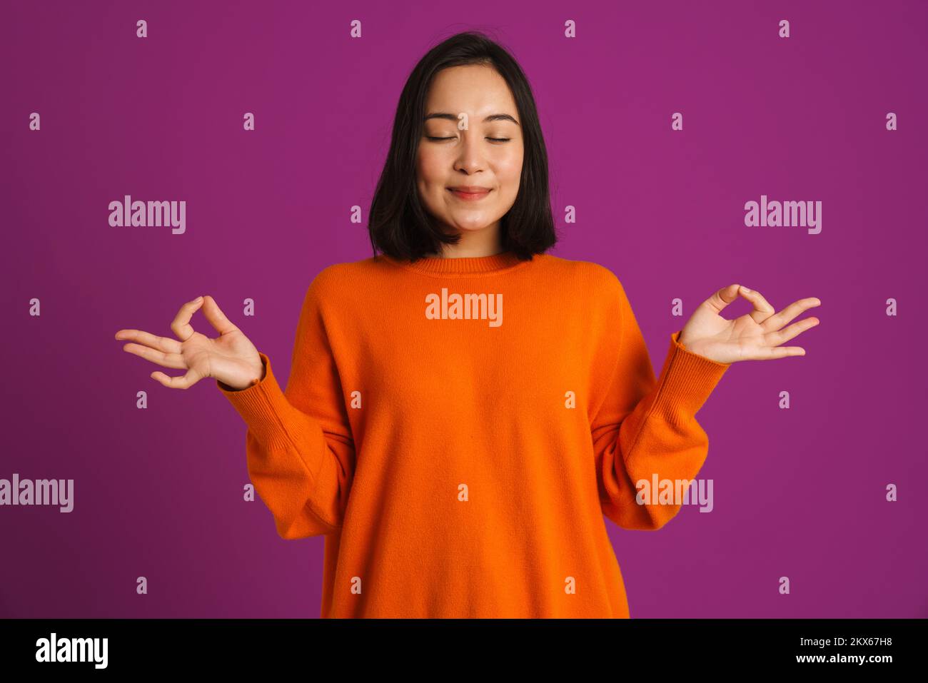 Young asian woman smiling and making zen gesture while meditating ...