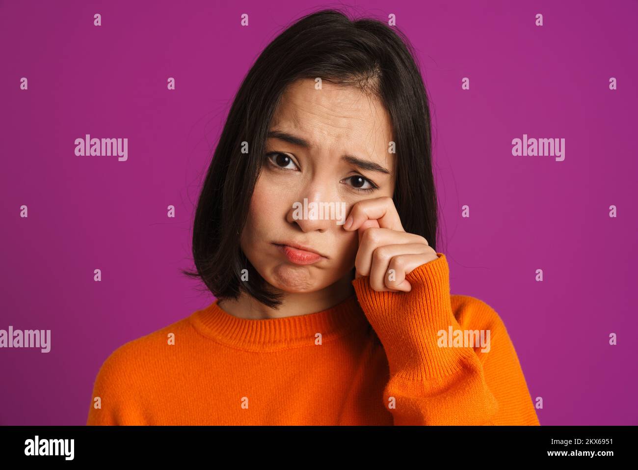 Young asian woman wearing sweater crying while wiping her tears ...