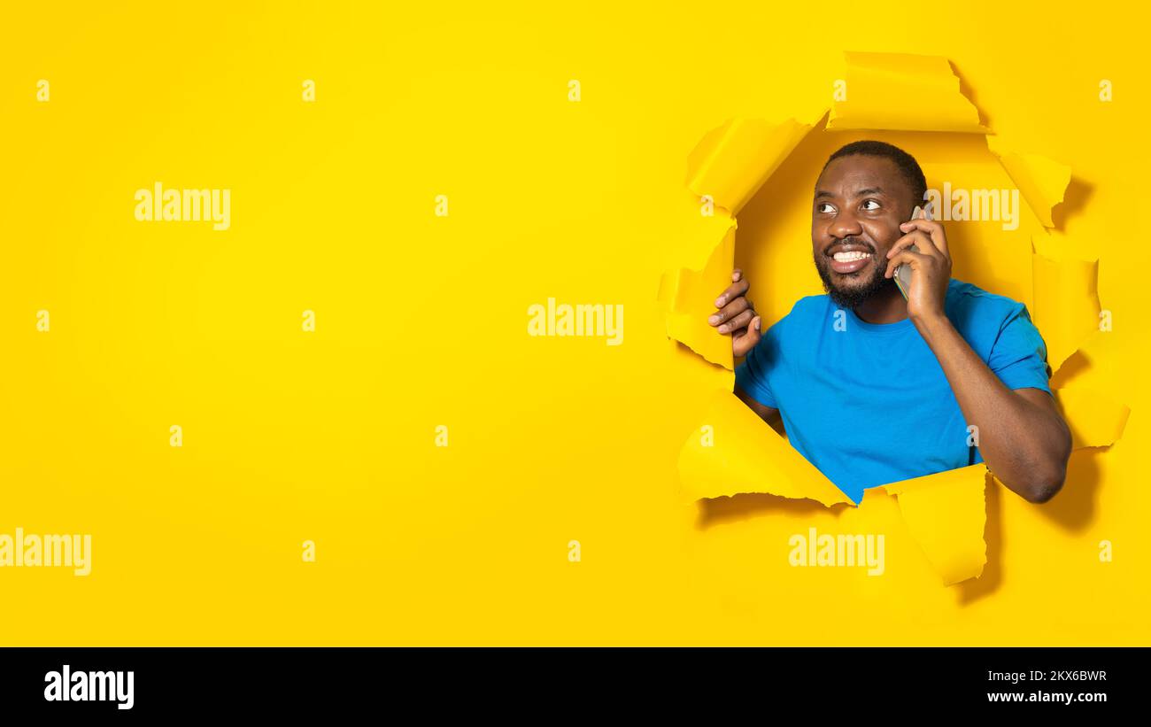Happy black man talking on cellphone and looking aside at free space ...