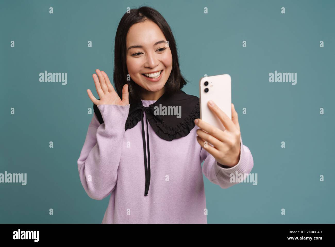 Young asian woman gesturing while taking selfie on cellphone isolated ...