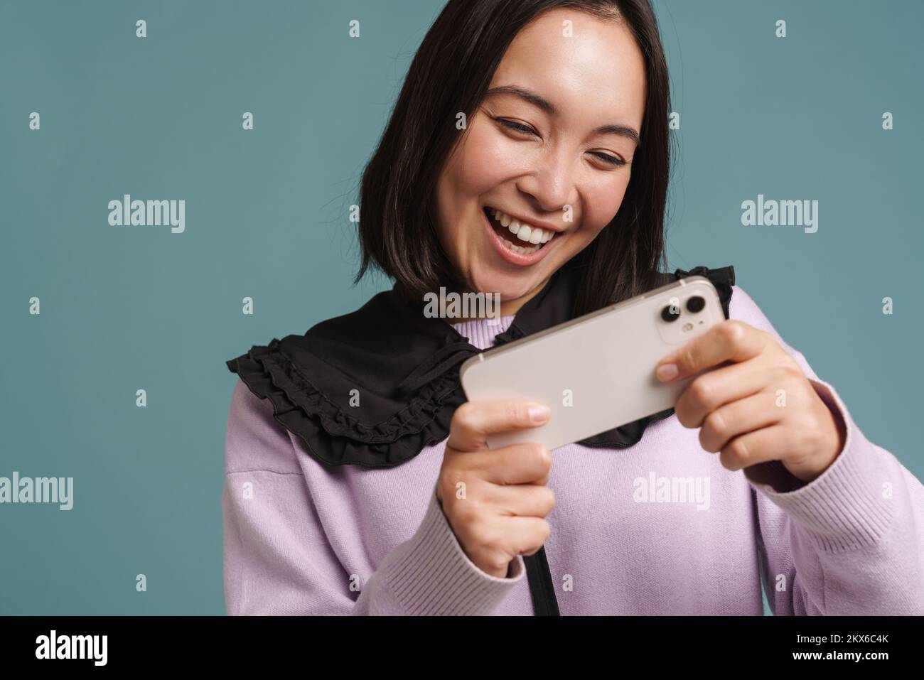 Young asian woman playing online game on mobile phone isolated over ...