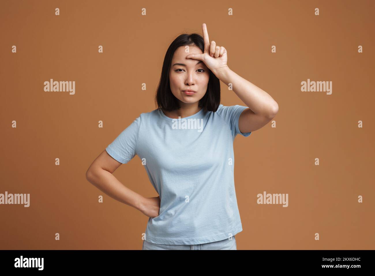 Young asian woman wearing t-shirt pointing finger upward isolated over ...