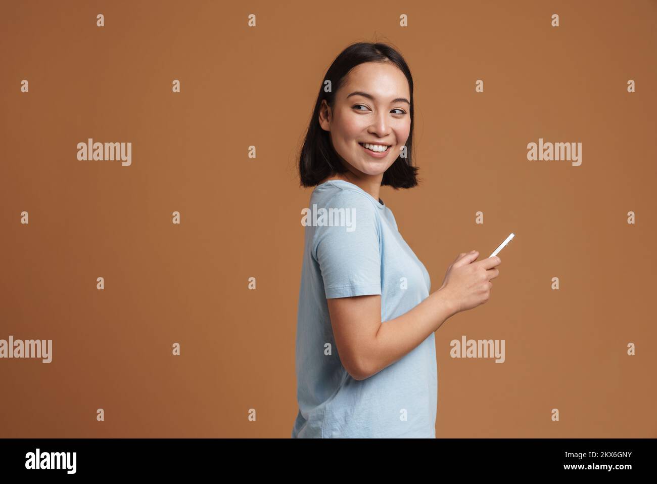Young asian woman wearing t-shirt laughing while using mobile phone ...