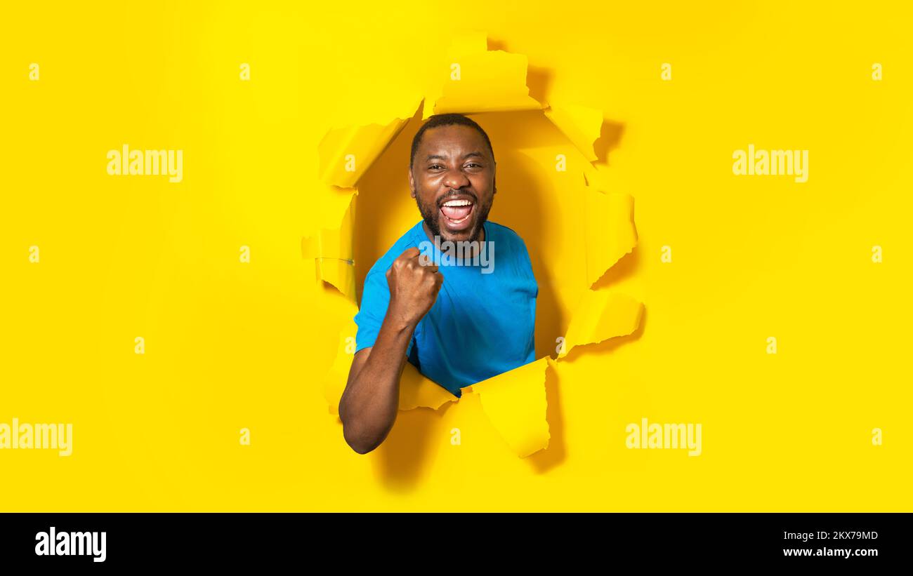 Overjoyed african american man raising clenched fist and shouting ...