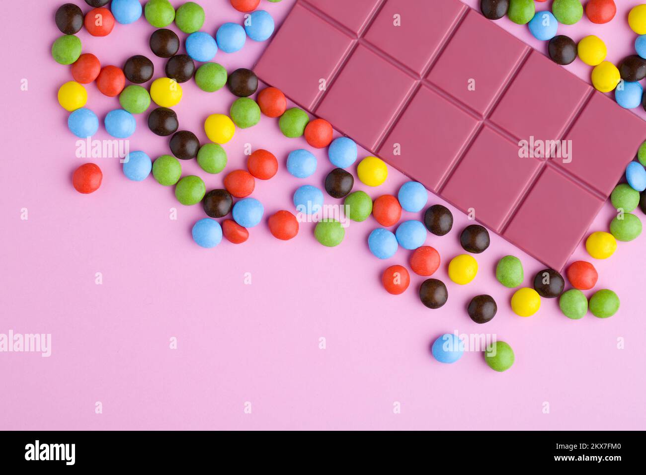 ruby chocolate bar with colorful chocolate candy tablets on pink ...