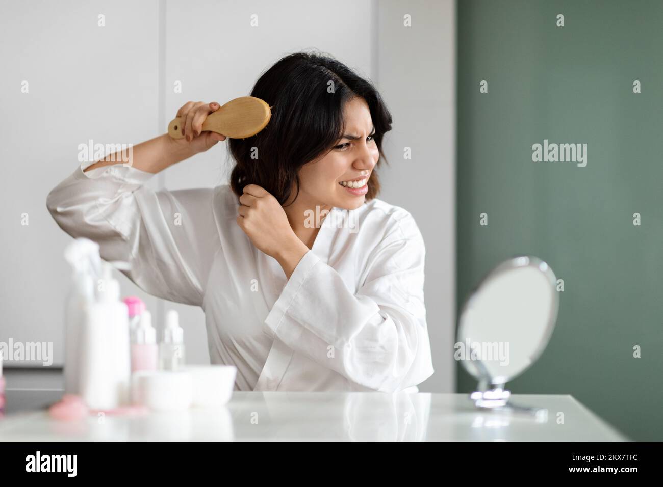 Angry lady brushing dry hair with hairbrush at home Stock Photo - Alamy