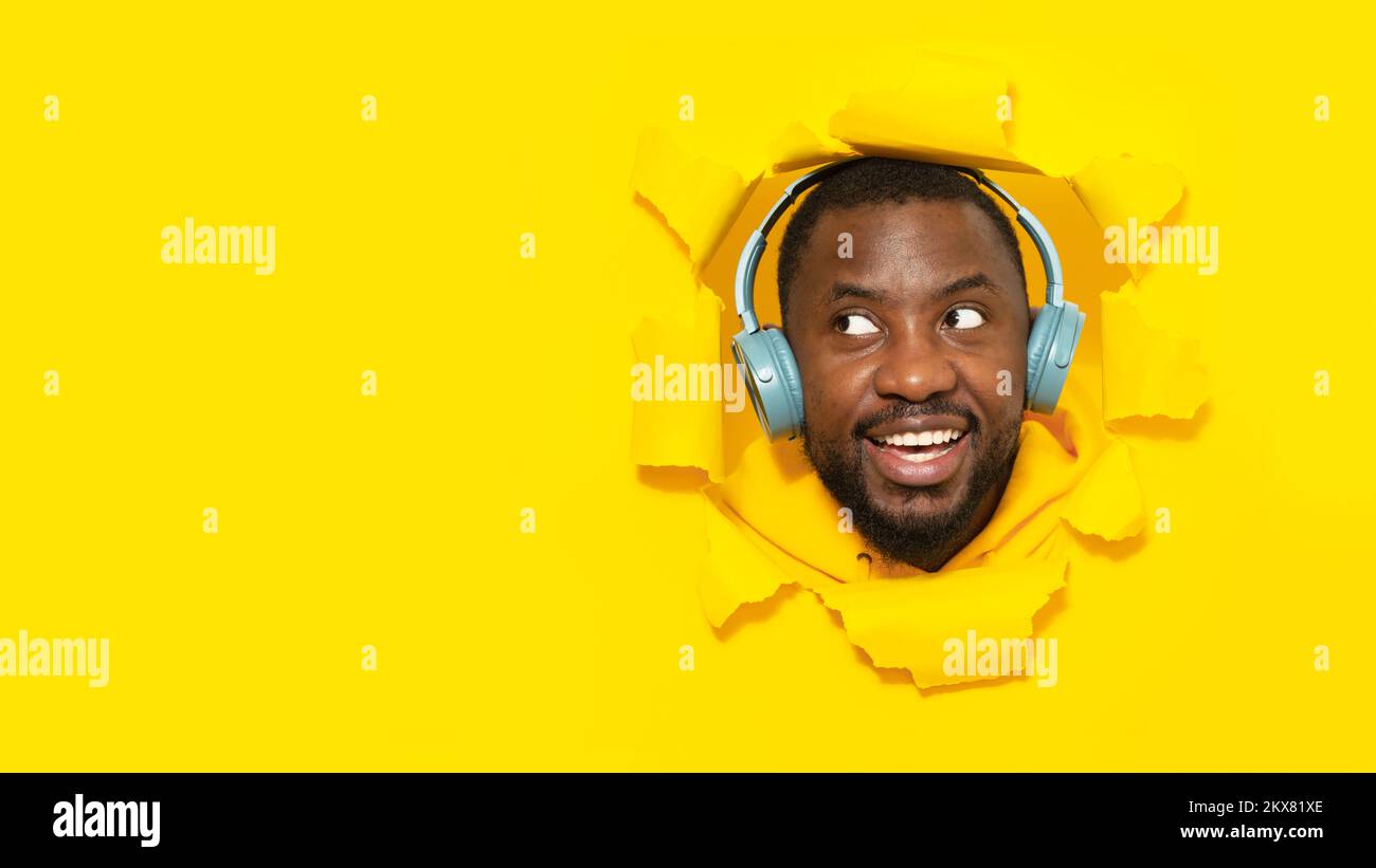 Black man wearing headphones, listening to music and looking aside at ...