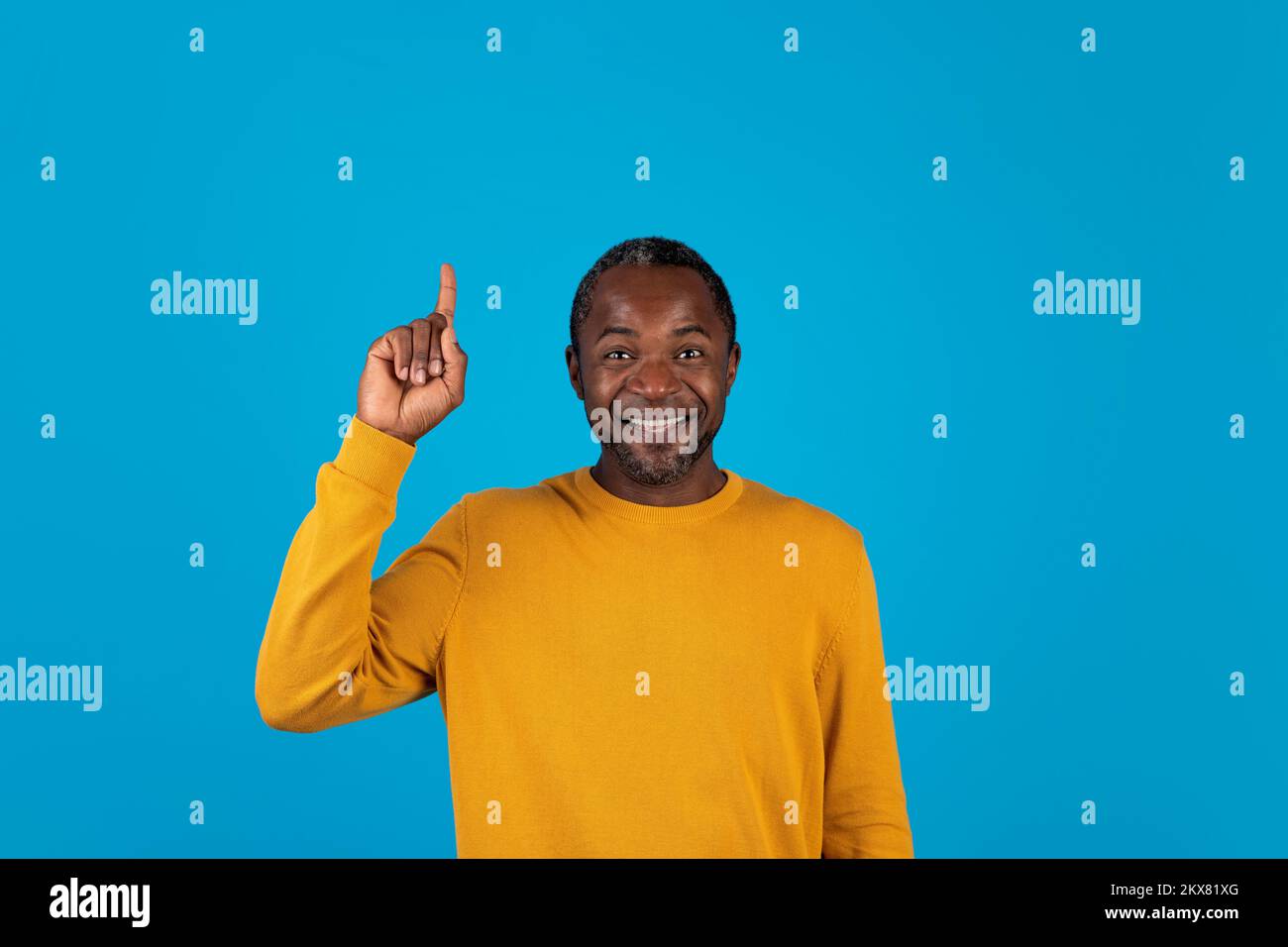 Happy african american man pointing upwards showing eureka gesture ...