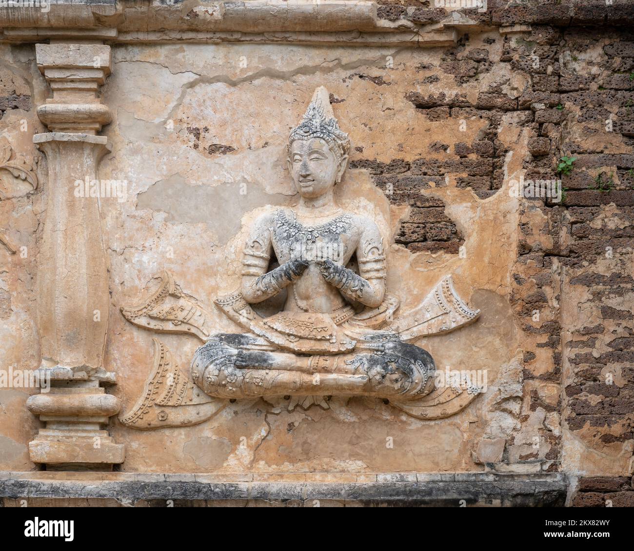 Ancient stucco life size carving of sitting deity on wall of Wat Chet ...