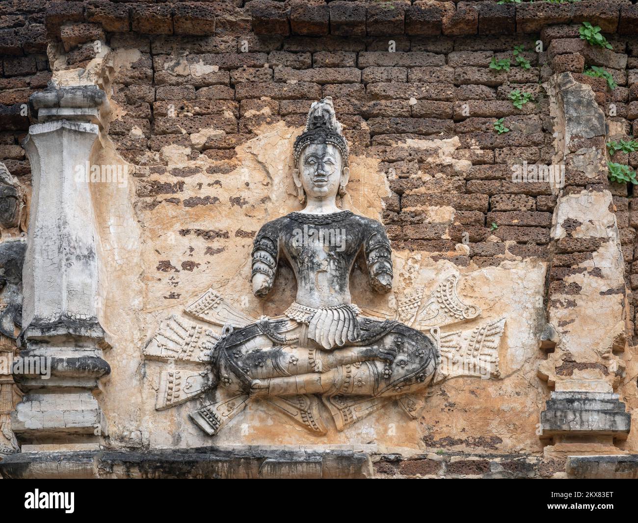 Ancient stucco life size carving of sitting deity on wall of Wat Chet ...