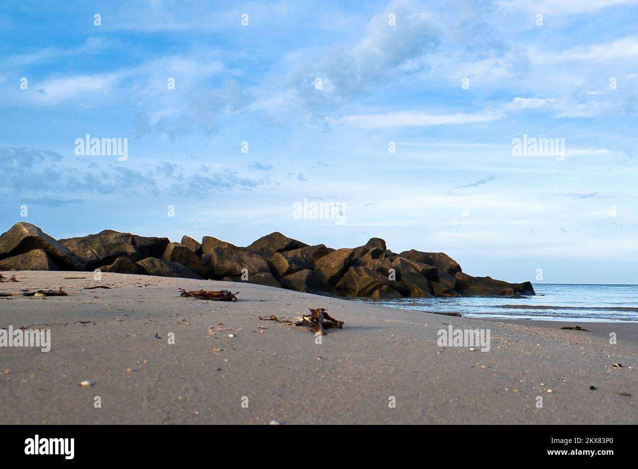 Stone groyne jutting into sea in Denmark with clouds in sky. Coastal ...
