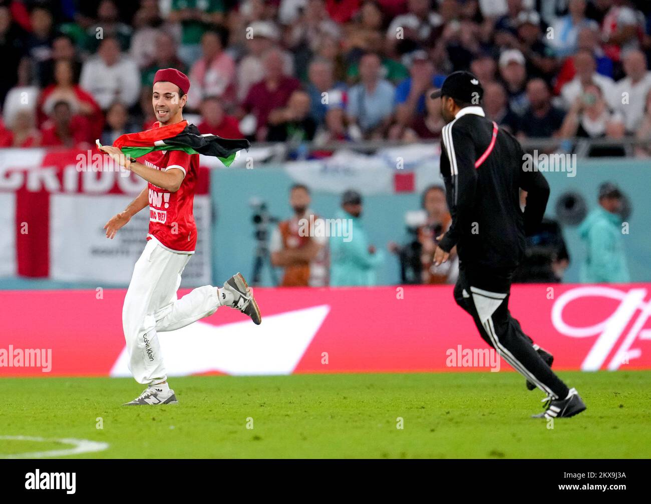 A member of security chases a pitch invader during the FIFA World Cup ...