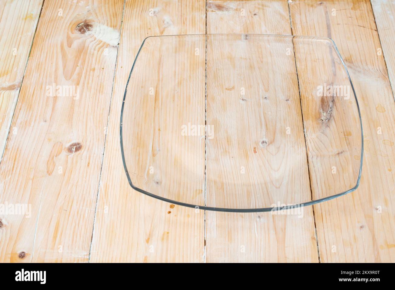 Transparent glass plate, square shaped on wood boards background, close ...