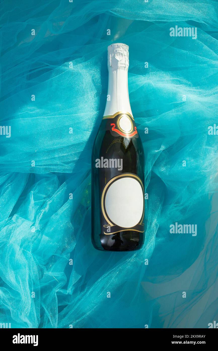 Champagne bottle with blank white label, on blue fabric background ...