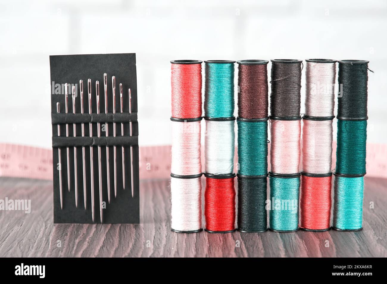 Pastel colored tailor threads stacked on the table with scissors and ...