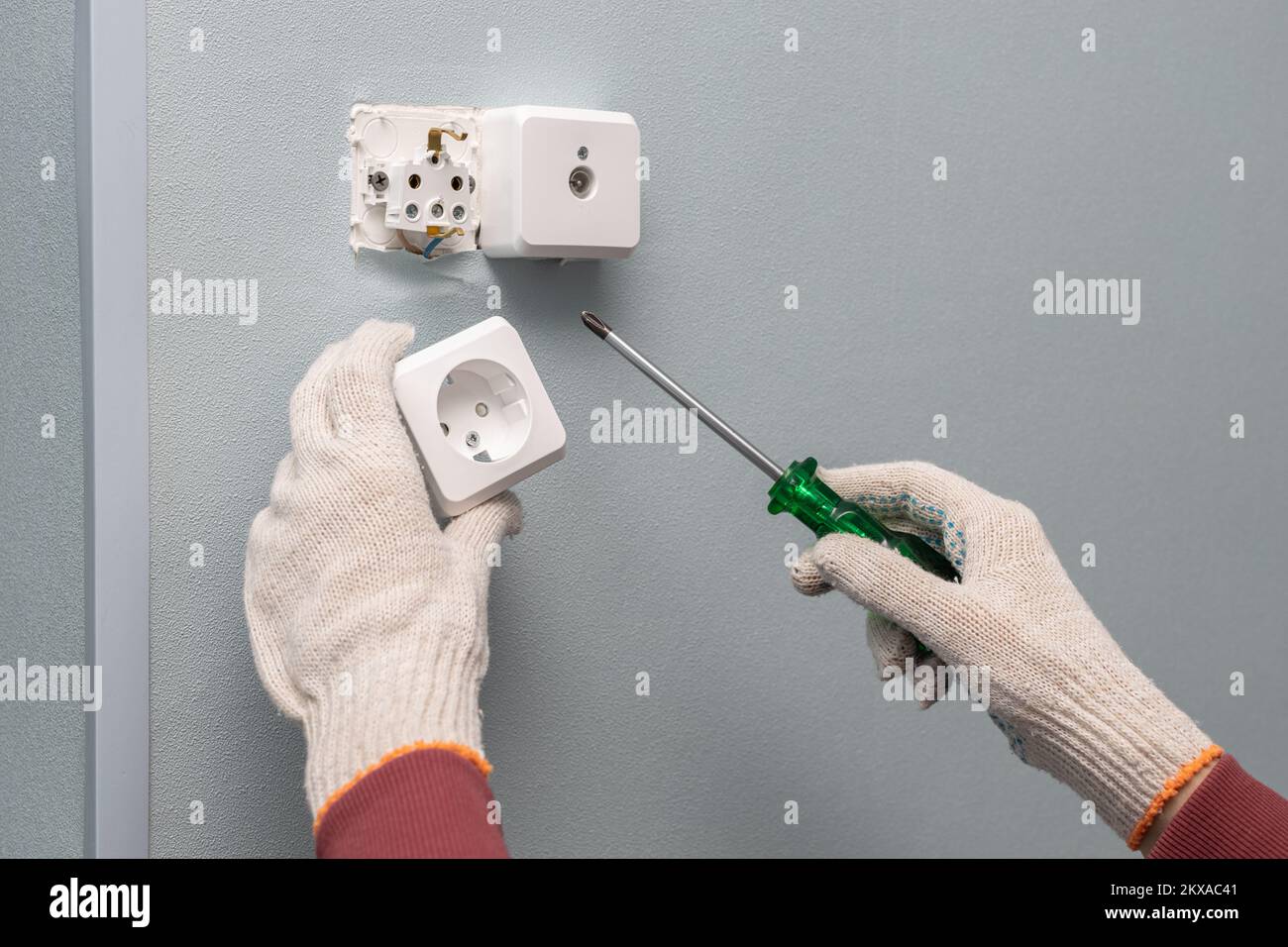 man repairing an electrical outlet with a screwdriver. man repairing a ...