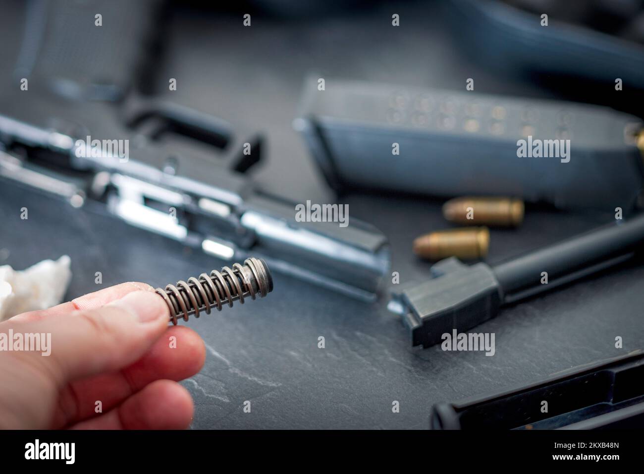 closeup of disassembled pistol and a hand holding recoil spring Stock ...