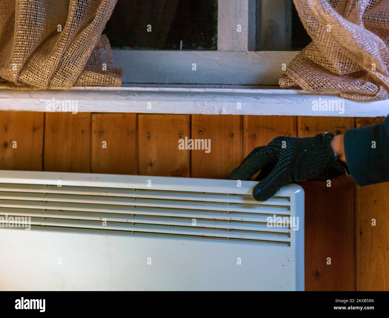 a hand in glove setting temperature on electric heater, hanging under ...