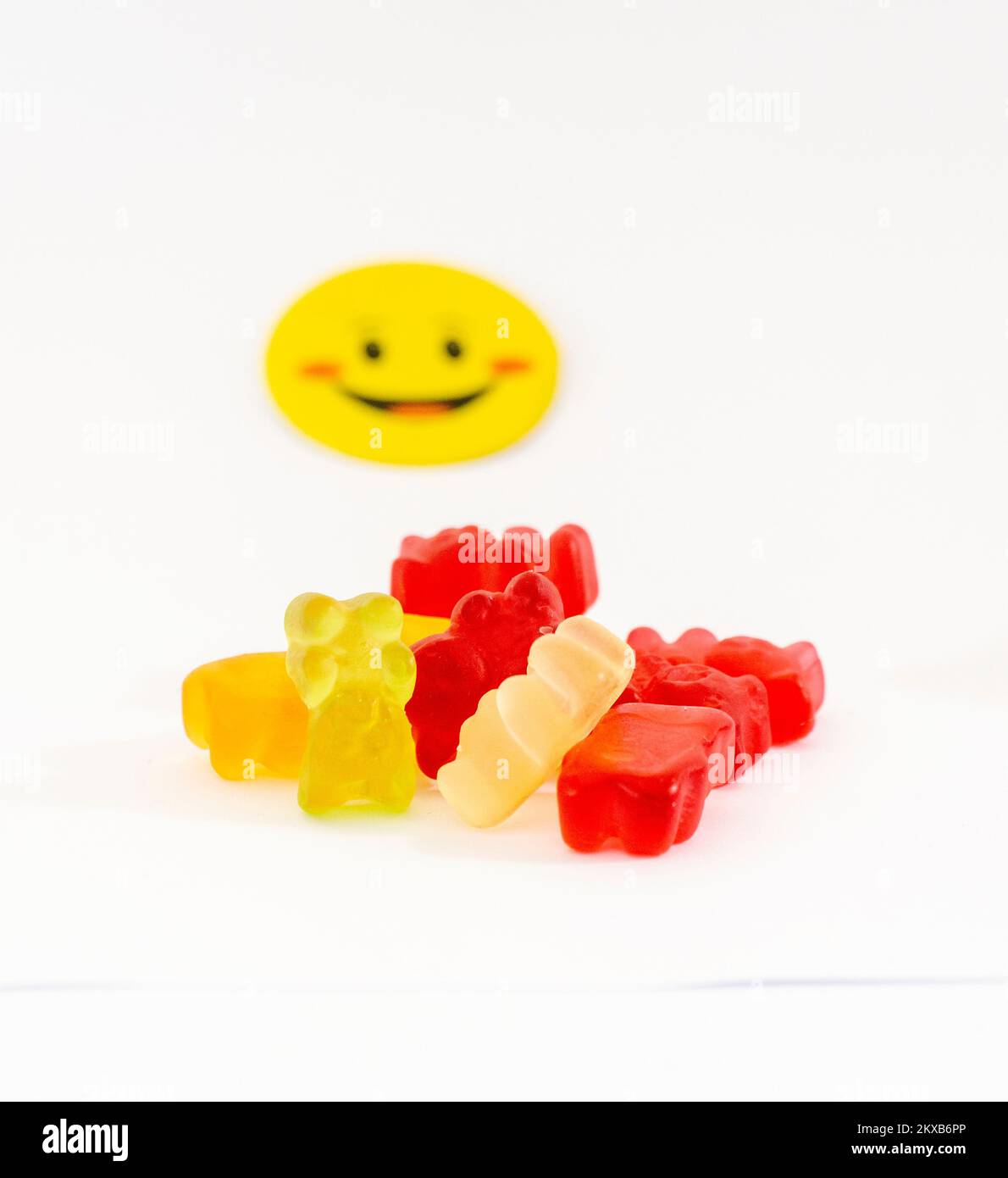 Group of colored gummy bear candy and yellow smiley stick isolated on a ...