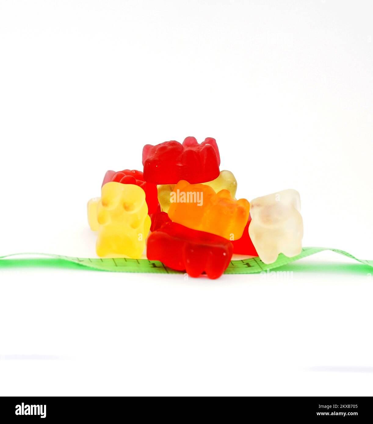 Group of colored gummy candies and tape measure isolated on a white ...