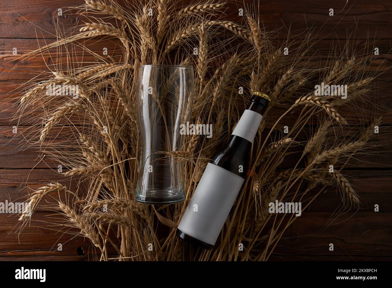 Bottle of beer and empty glass lie on the ears of rye. Concept of ...