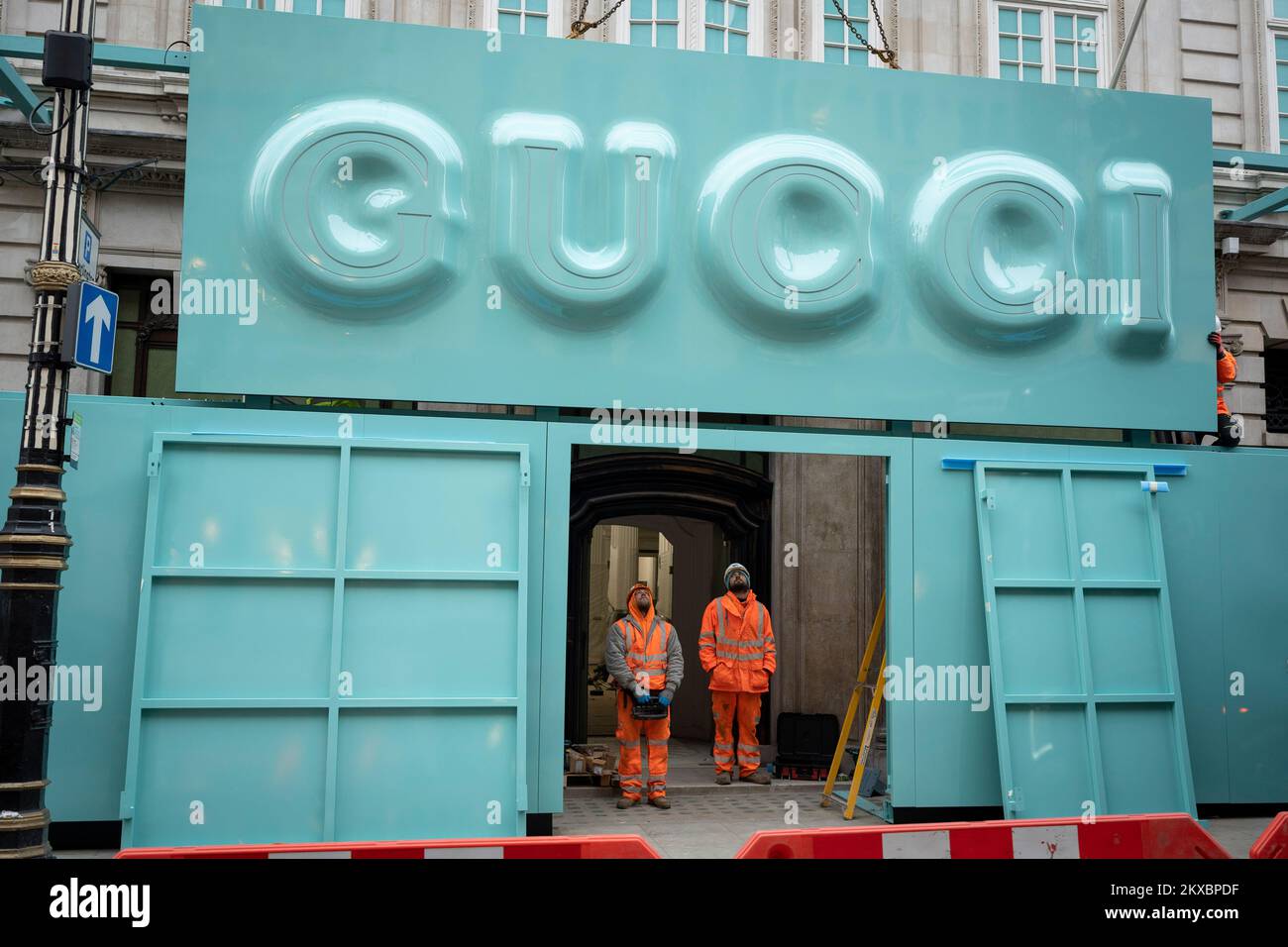 Workmen check clearances while the Gucci logo is positioned above the ...