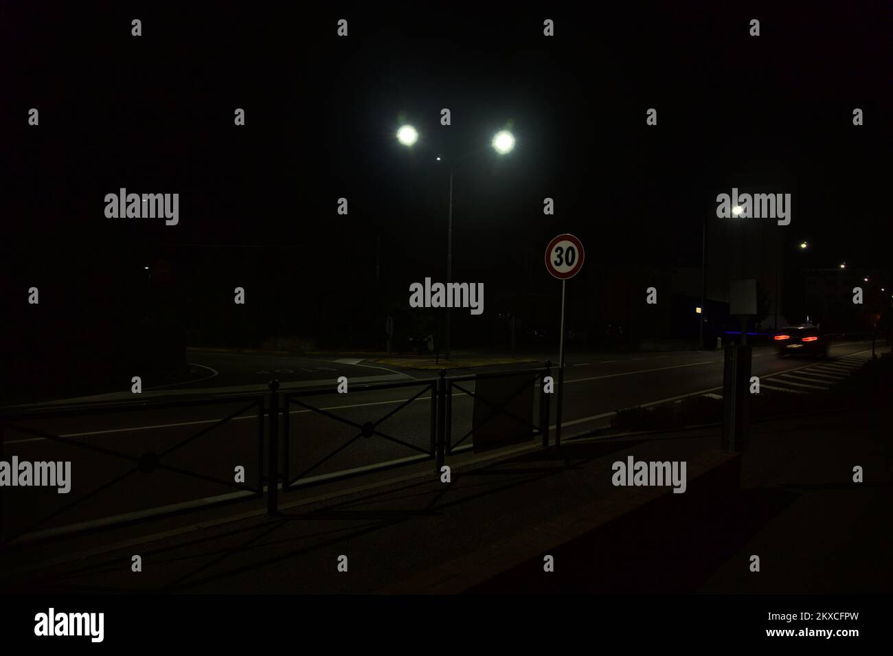 Road next to a crossing at night with cars passing by Stock Photo - Alamy