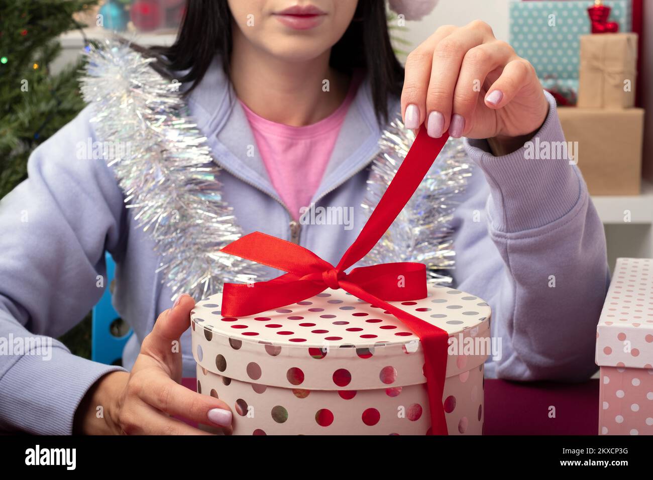 woman unwrap red ribbon on gift box in cylindrical shape Stock Photo ...