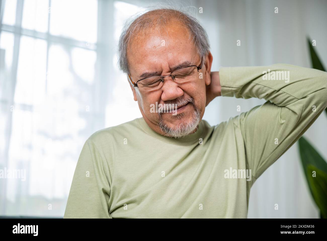 Old man suffering from nape neck pain at home Stock Photo - Alamy